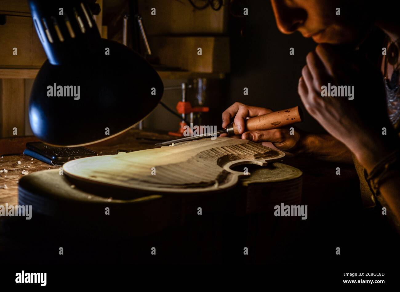 Young attractive female violin maker luthier carving a violin table ...