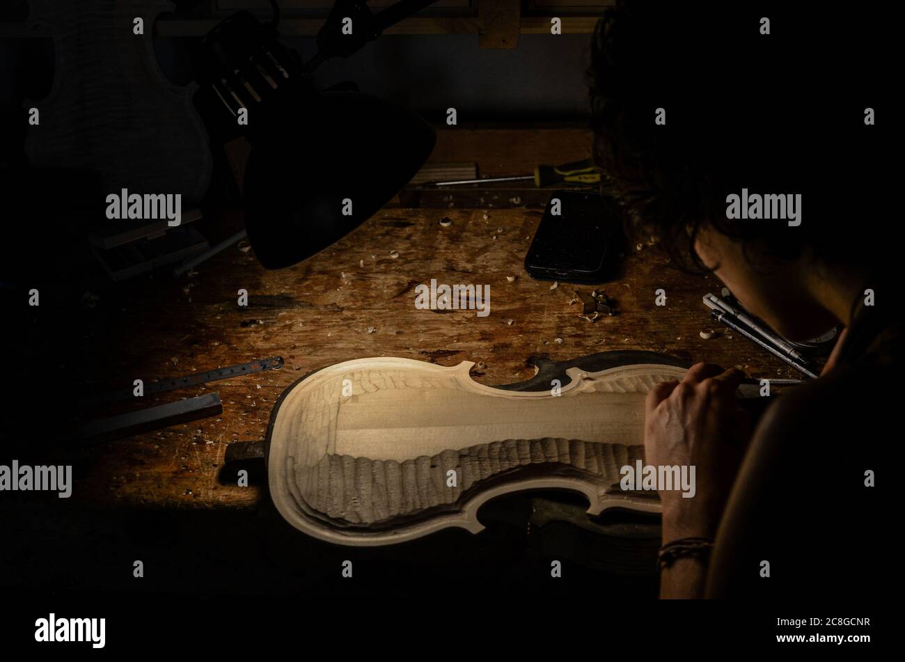 Young attractive female violin maker luthier carving a violin table ...