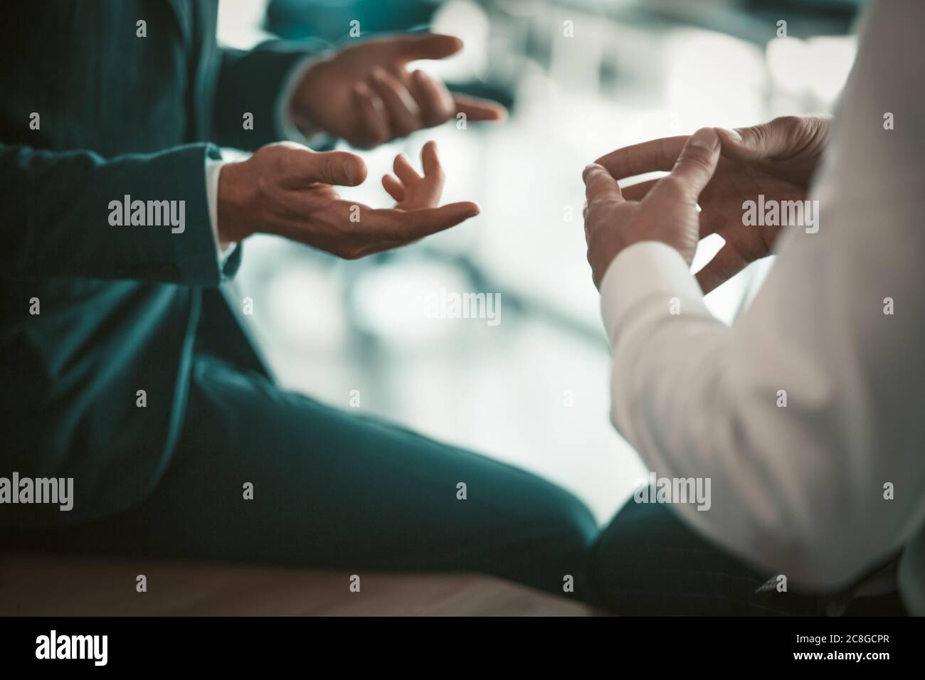 Two business people have conversation sitting on office desk. Close up ...