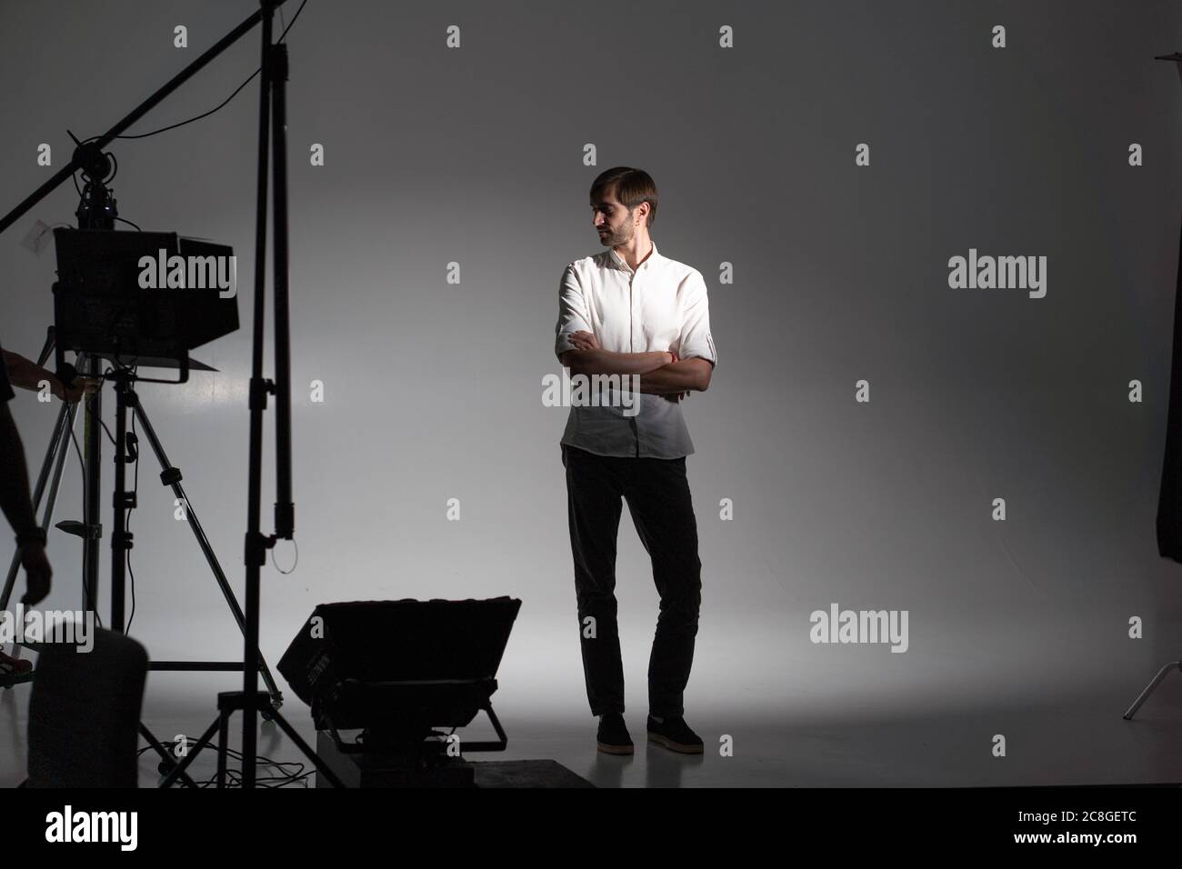 Young man posing on white background among the studio equipment ...