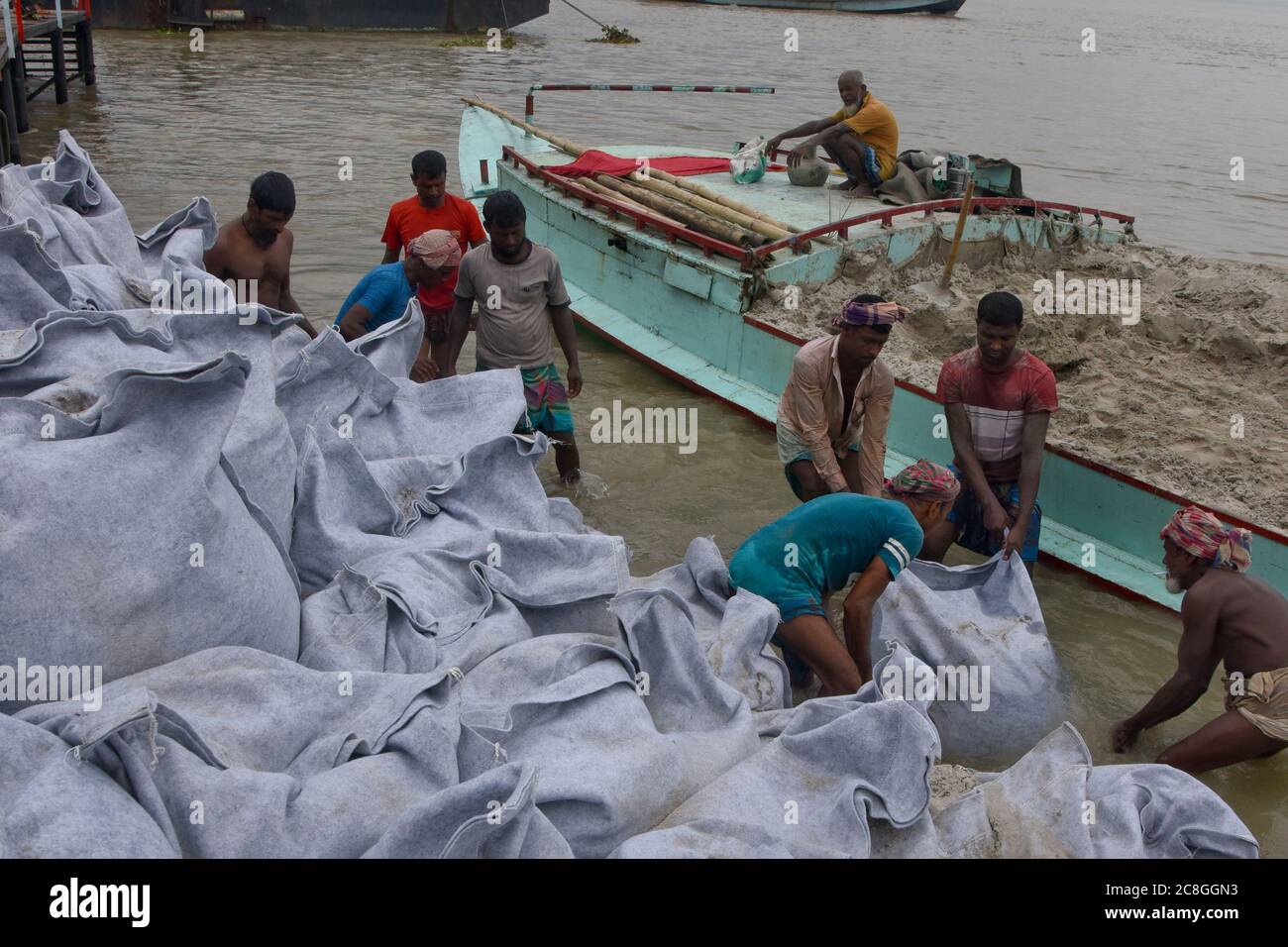 Workers prepare sandbags to repair the embankment designed to protect ...