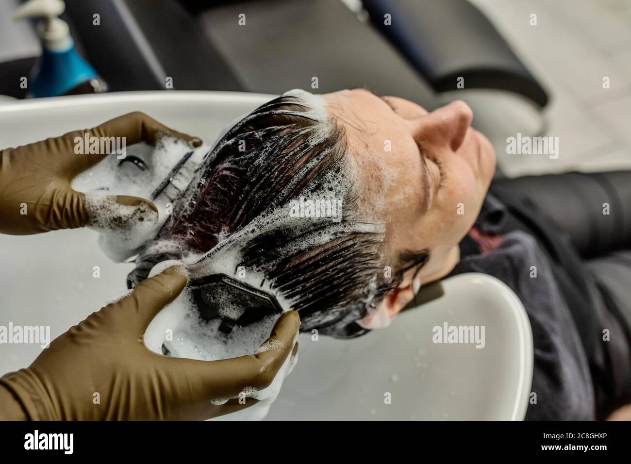 Customer in a hairdressing salon gets her hair washed with shampoo by a ...