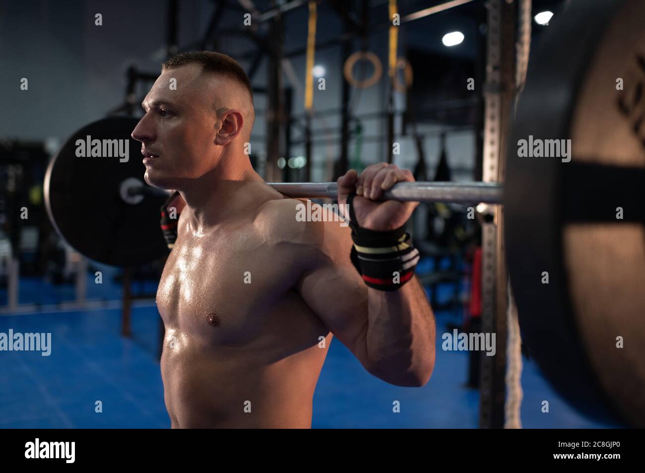 Muscular adult athlete with heavy barbell doing back squat exercise in ...