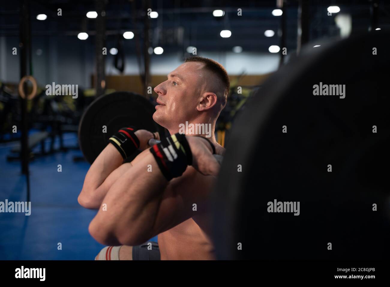 Side view of strong adult athlete doing front squat with barbell in gym ...