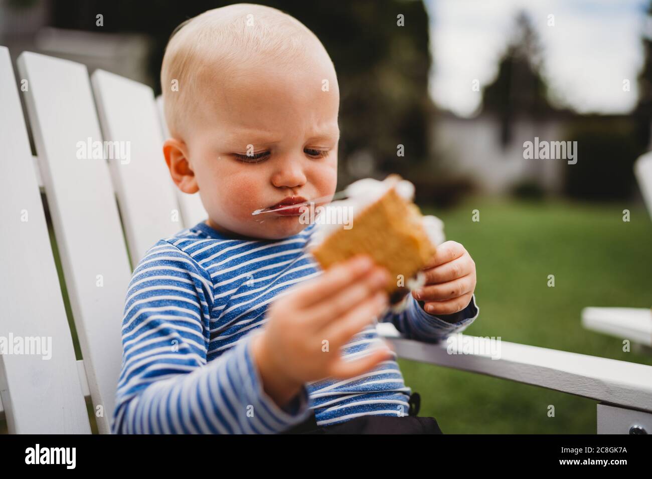 Close up of young boy eating smores with string of melted marshmallows ...