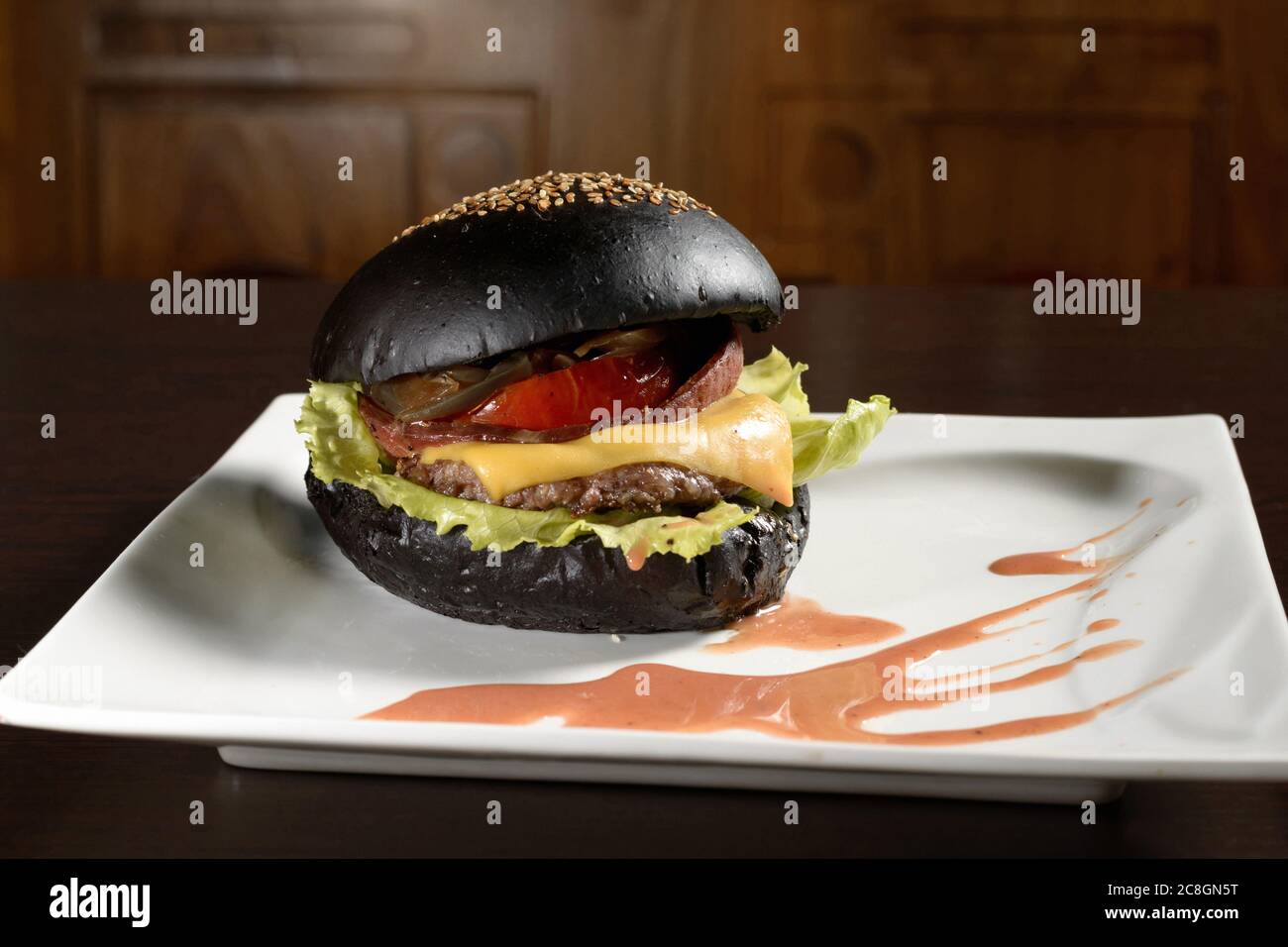Black cheeseburger with beef Patty on square plates and wooden table ...