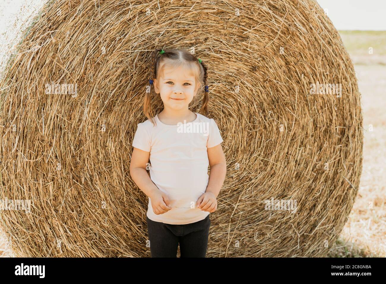 little girl playing by the haystack on a sunny summer day Stock Photo ...