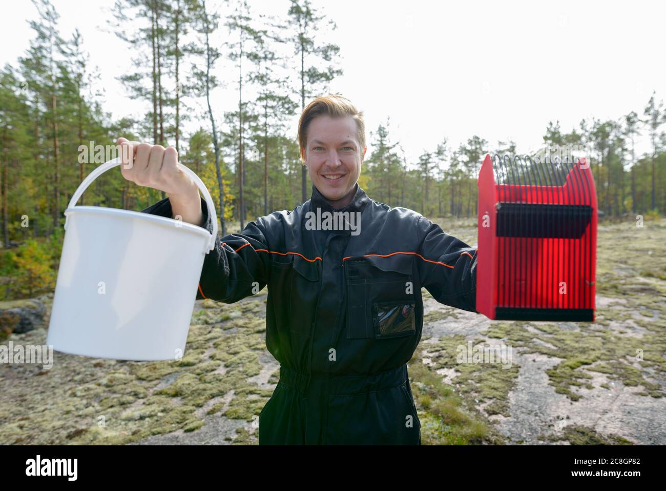 Portrait of happy young handsome man holding bucket and berry picker in ...