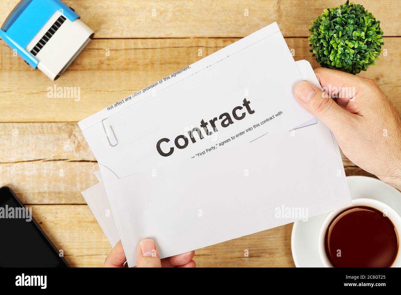 hands holding an envelope containing a contract over his desk Stock ...