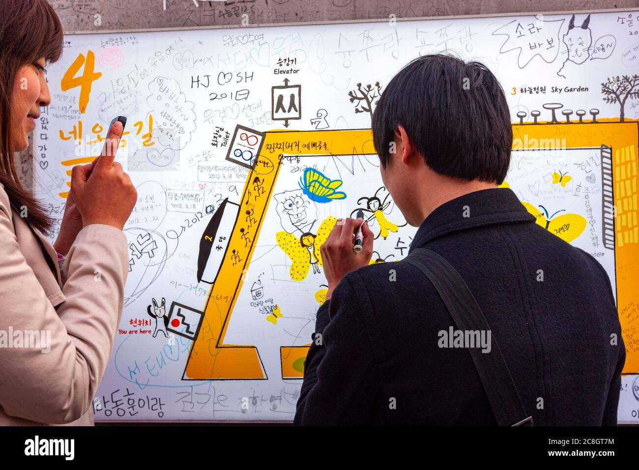 Girl taking picture to a boy drawing in a panel hi-res stock ...