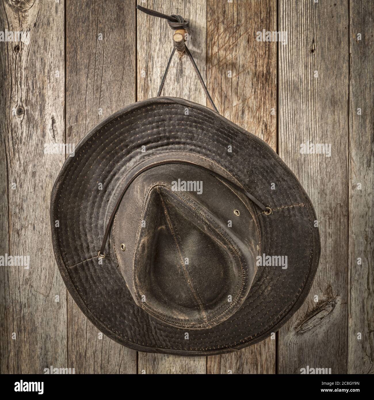 weathered outback oilskin hat hanging on rustic barn wall ...