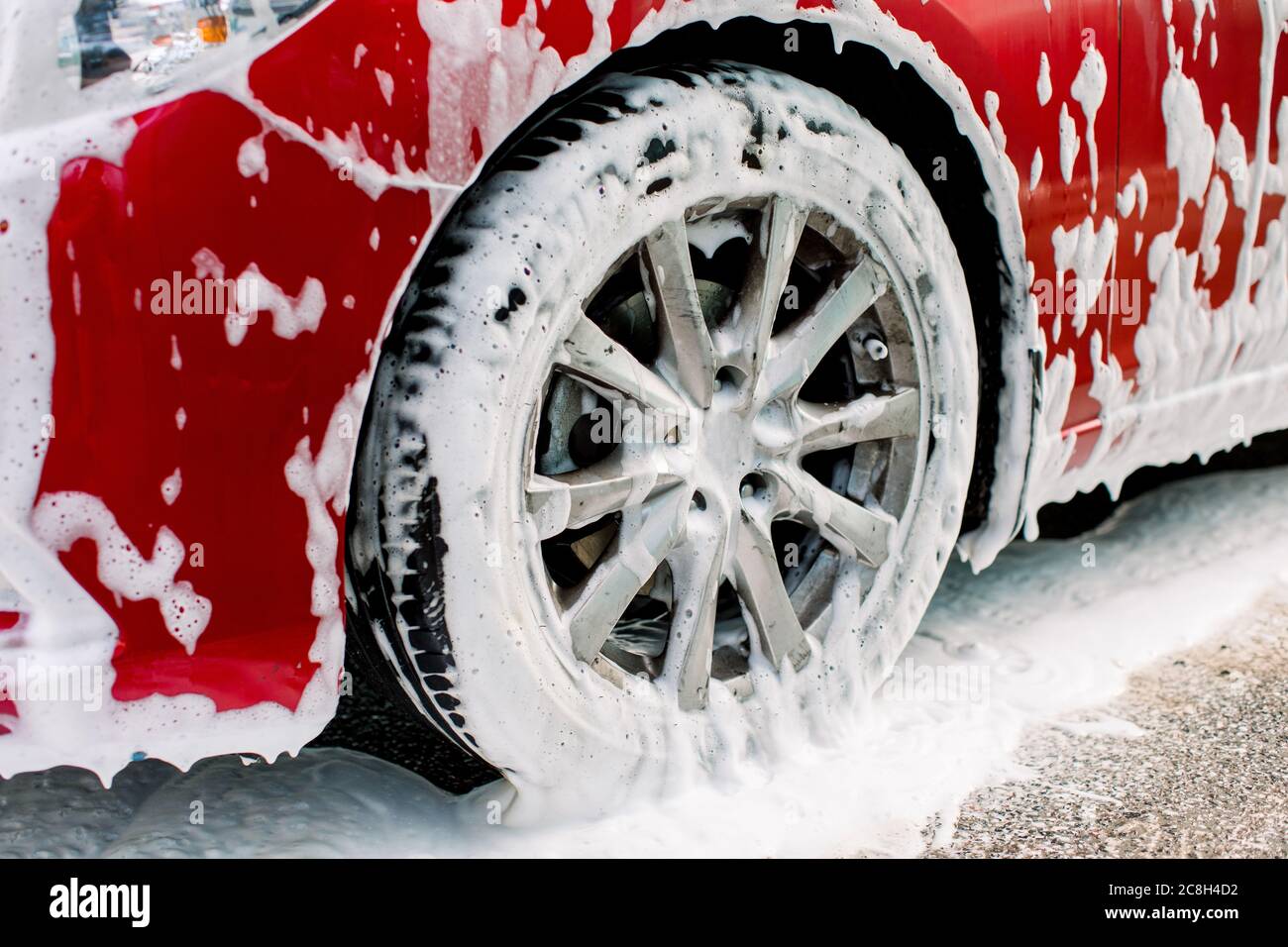 Cropped image of wheel of luxury red car in outdoors self-service car ...