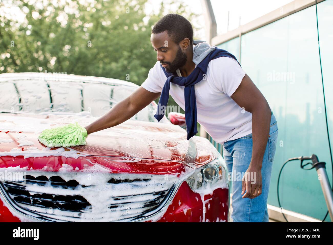 Outdoor car wash self service. Handsome young African man washing ...