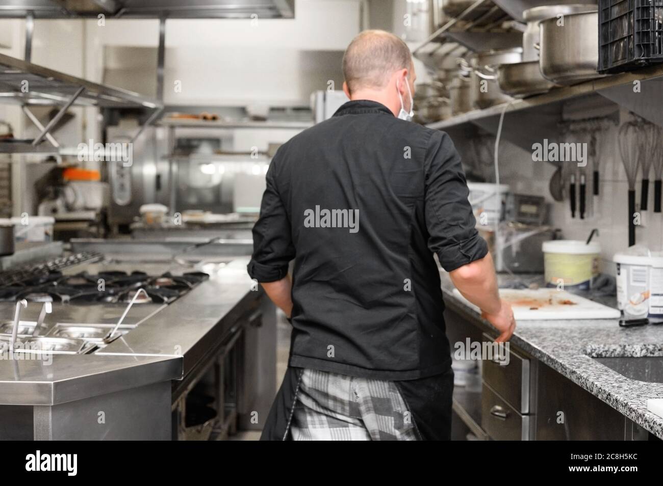 Chef in uniform cooking in a commercial kitchen. Male cook wearing ...