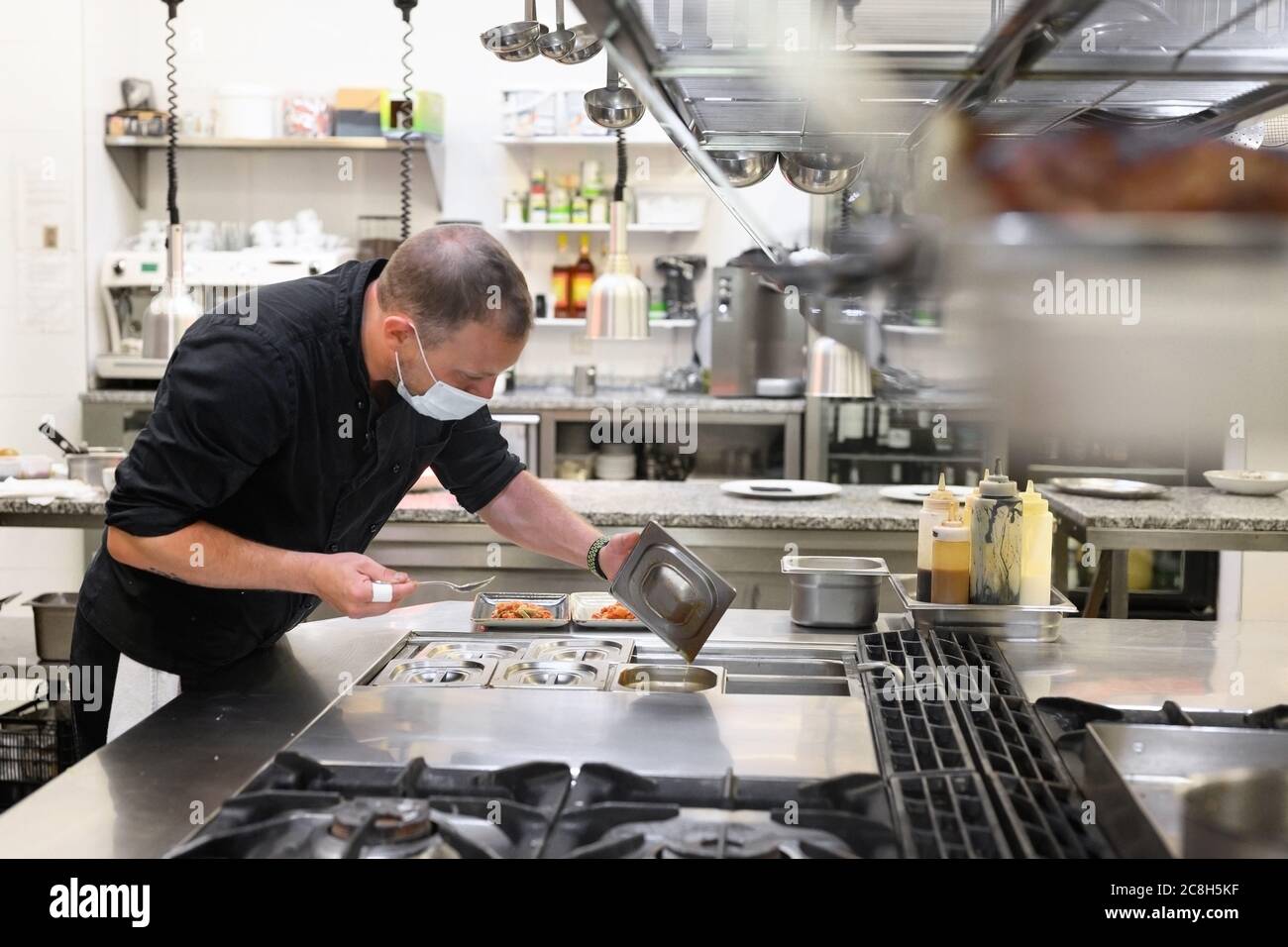 Chef in uniform cooking in a commercial kitchen. Male cook wearing ...