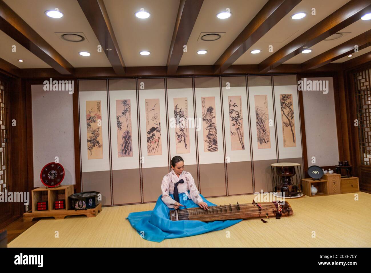 A Korean woman wearing a traditional Hanbok , playing the Geomungo at ...