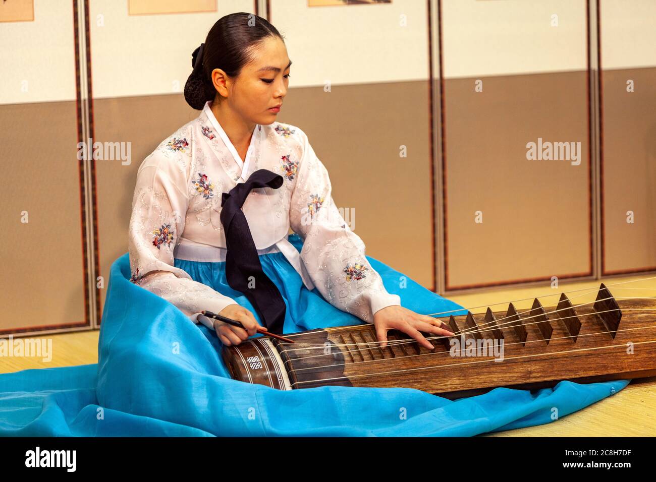 A Korean woman wearing a traditional Hanbok , playing the Geomungo at ...