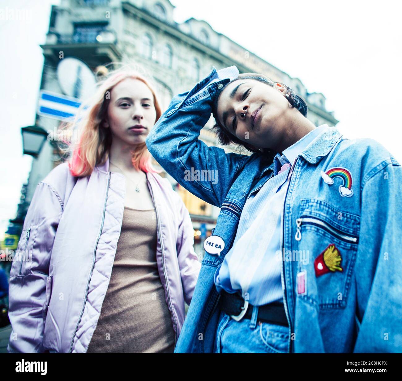 Two teenage girls infront of university building smiling, having fun ...