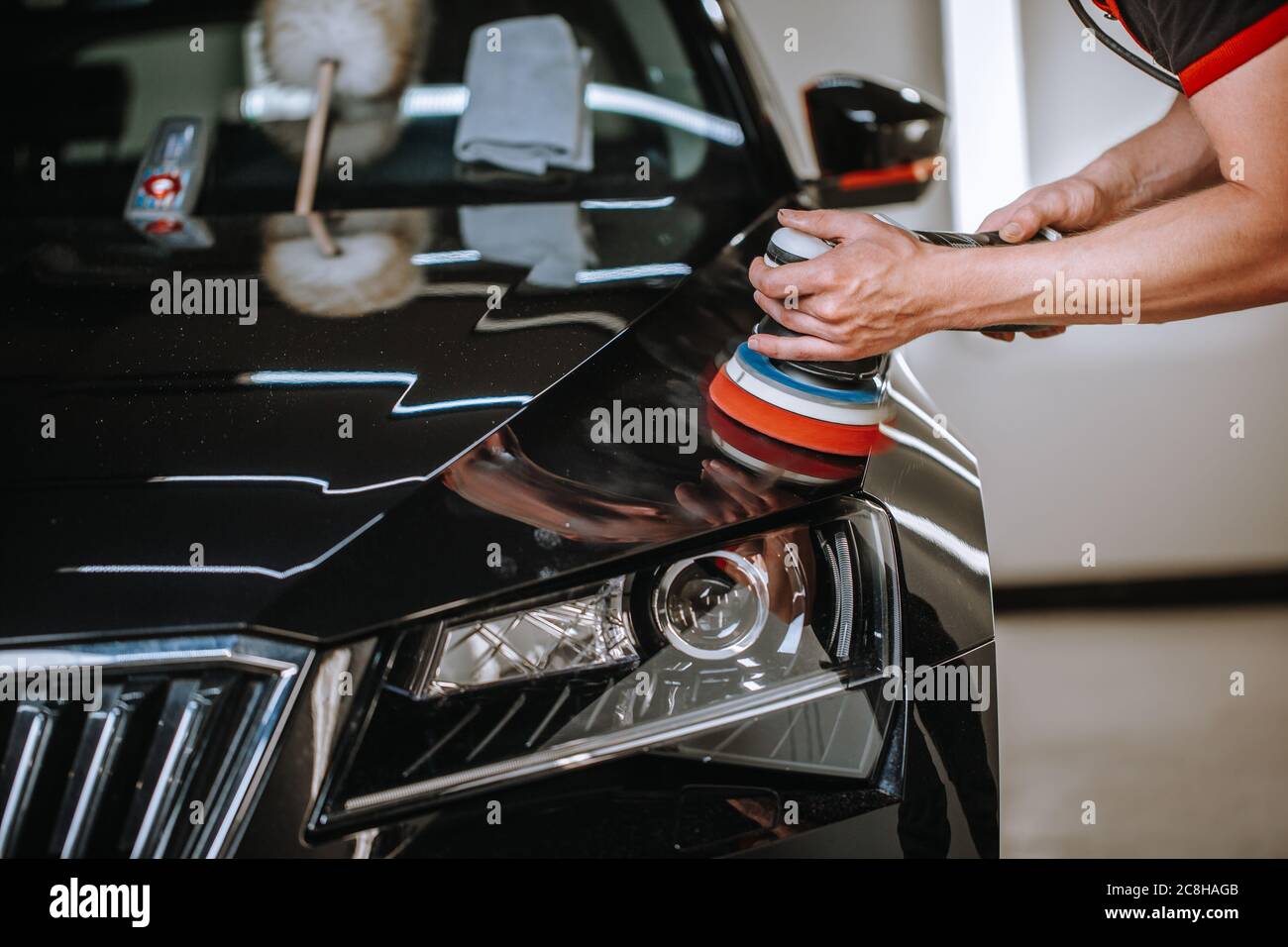 Professional detailing a car in car studio, hands with orbital polisher ...