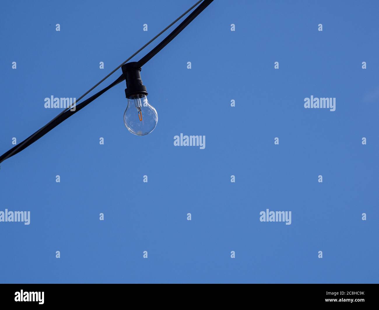 a bulb of a black chain of lights in front of a blue sky Stock Photo ...