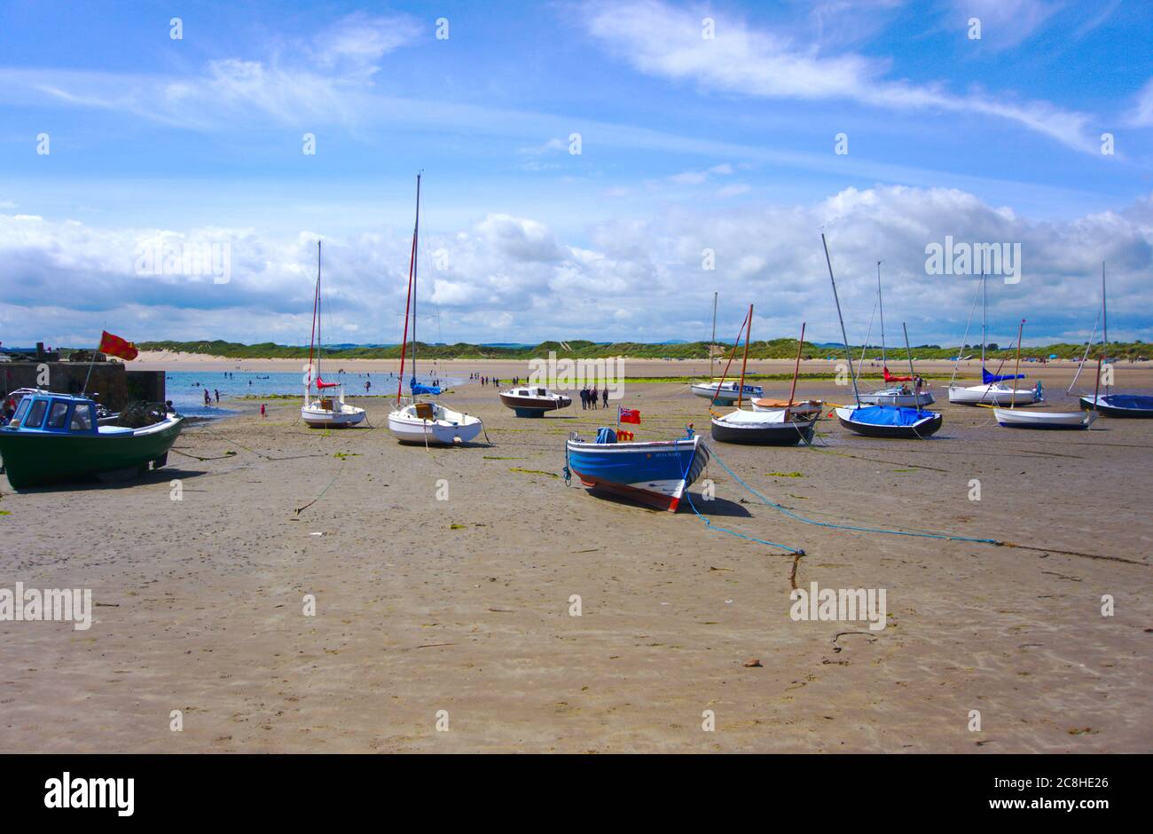 Boats on the sand during low tide at Beadnell beach, Northumberland, UK ...