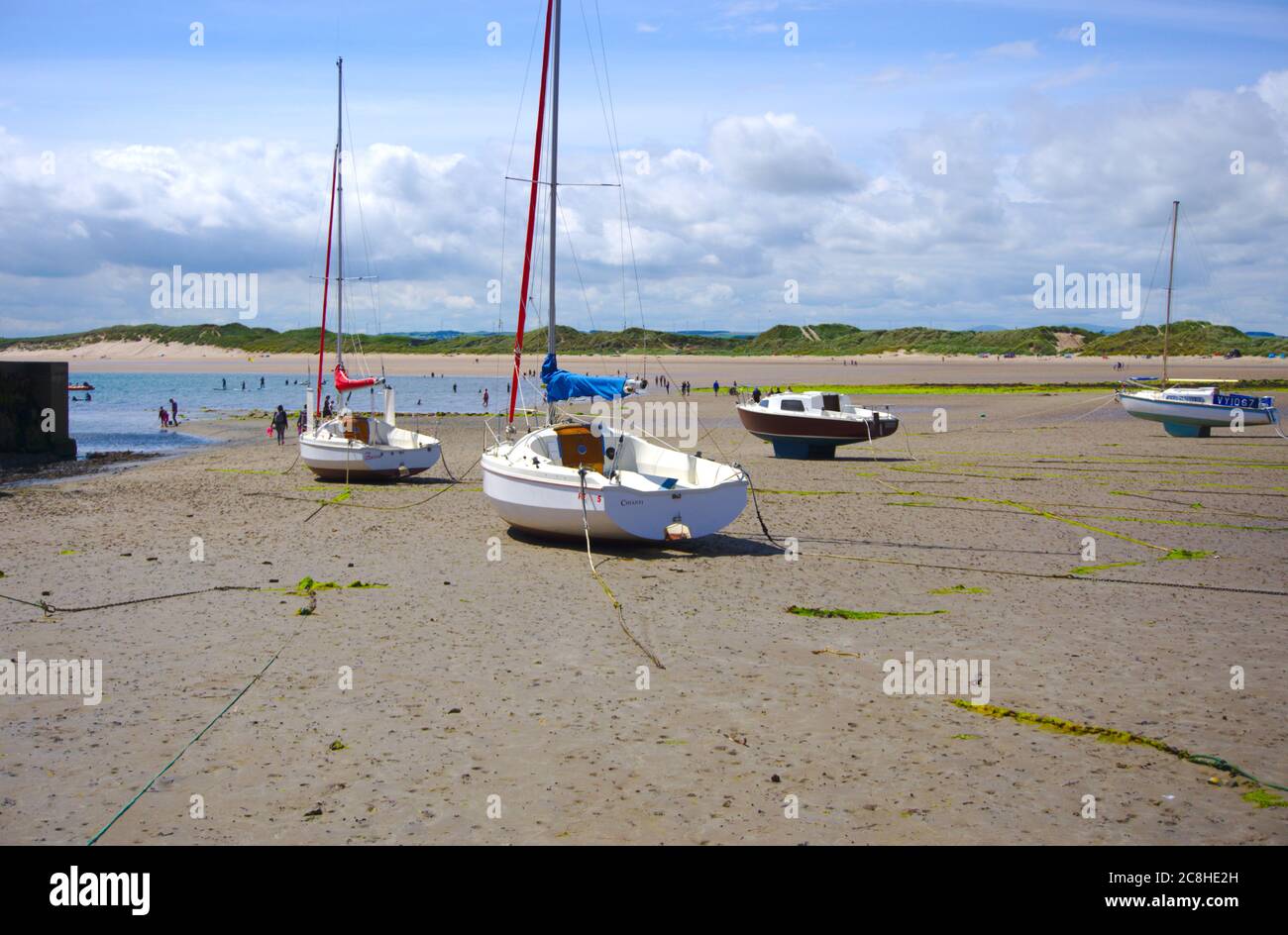 Boats on the sand during low tide at Beadnell beach, Northumberland, UK ...
