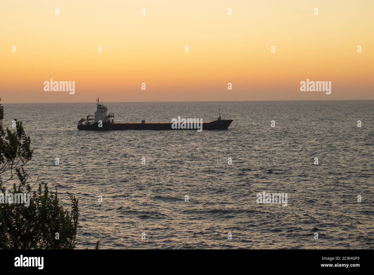 sad cargo ship going alone at sunset Stock Photo - Alamy