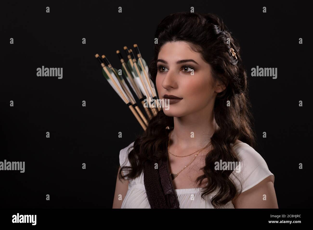 Close-up portrait of a archer woman in white dress on black background ...
