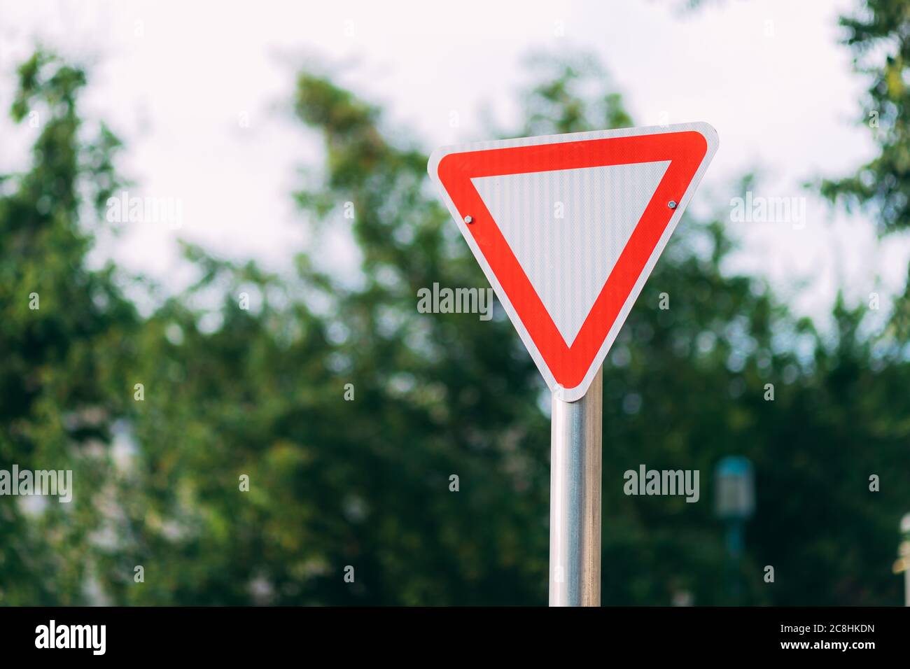 Sign give way on a blurred street and white sky. Red and white road ...