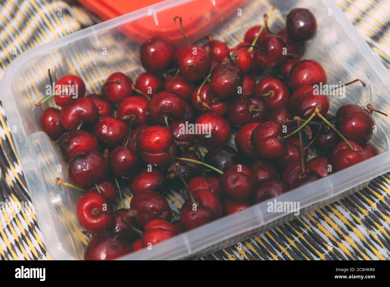 Ripe sweet cherries in a boxing box on a bedspread on the beach. Cherry ...