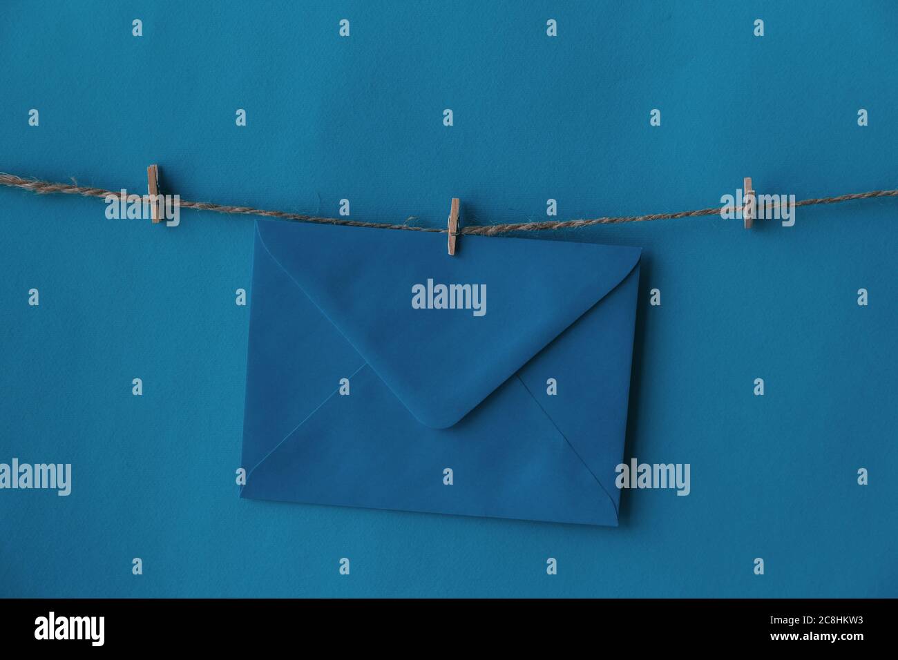 One closed blue envelope hanging on rope isolated blue background ...
