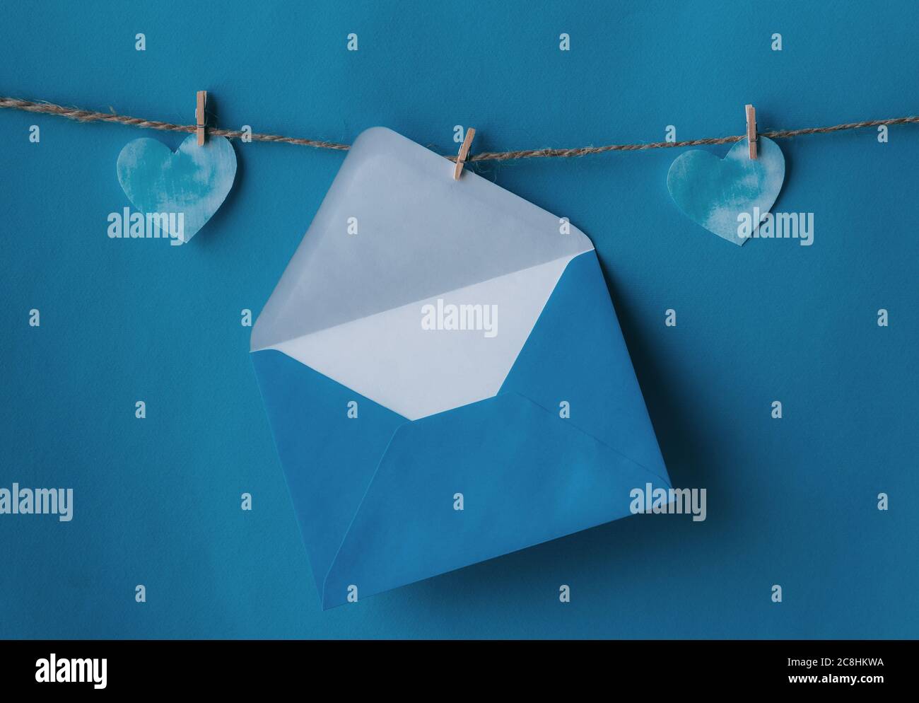 One opened blue envelope hanging on rope isolated blue background with ...