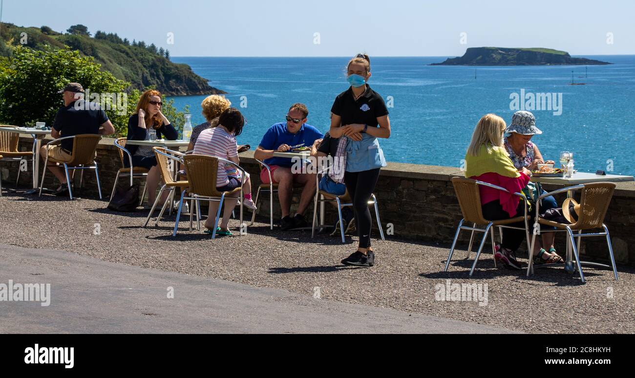 Waitress young woman wearing PPE serving customers eating outdoors ...