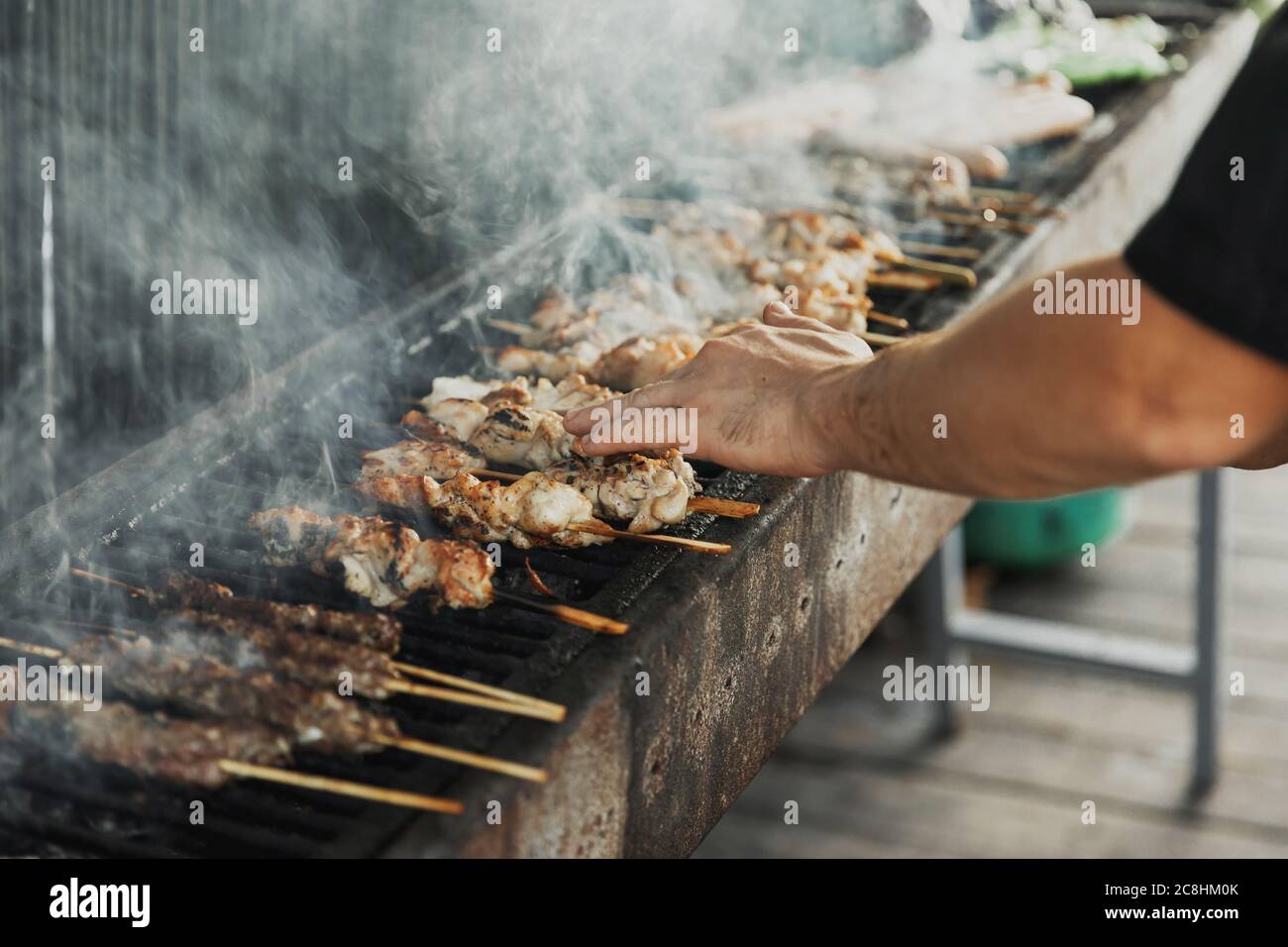 Hand of young man grilling some meat and vegetables on long rectangular ...
