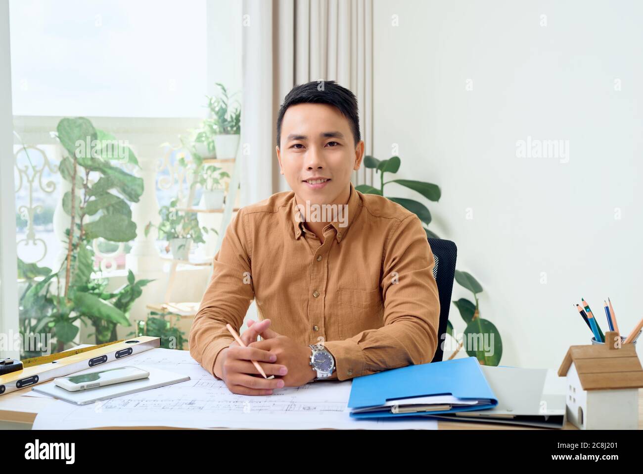 Portrait of young Asian architect man woking with blueprint at his ...