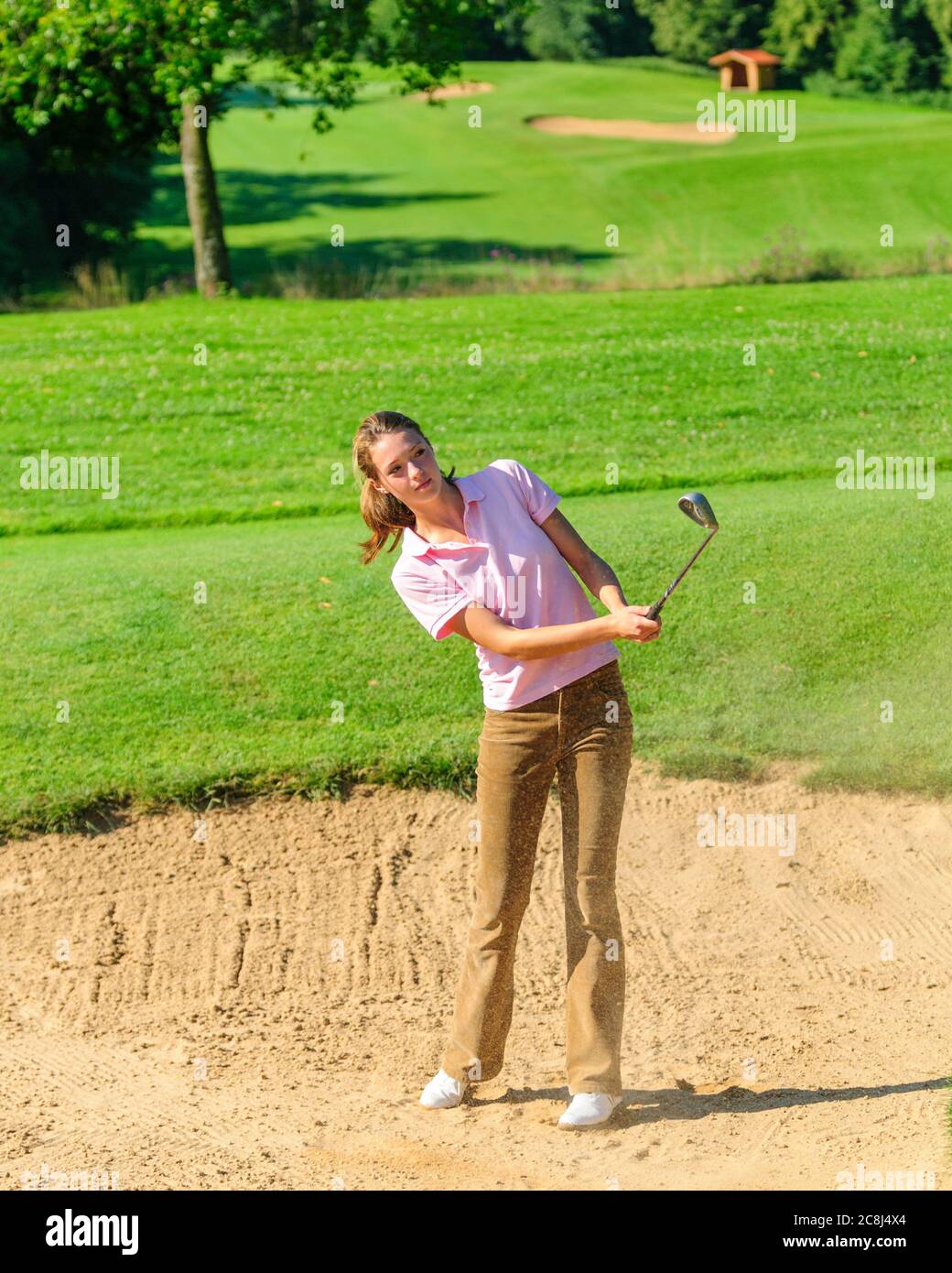 Young female golf player playing ball in sand bunker Stock Photo - Alamy