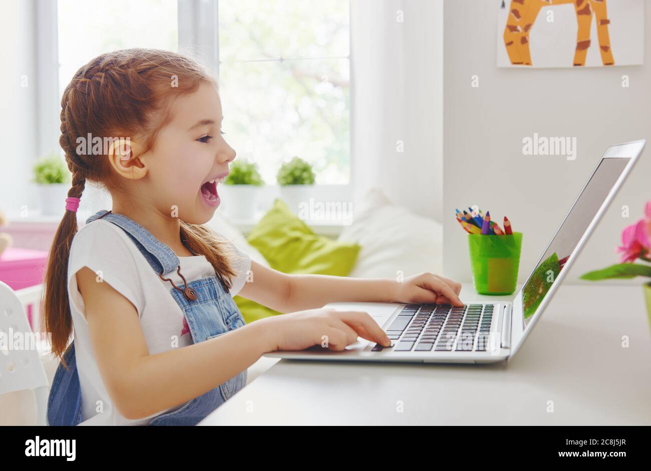 Child little girl with a laptop computer at home. Happy little child ...