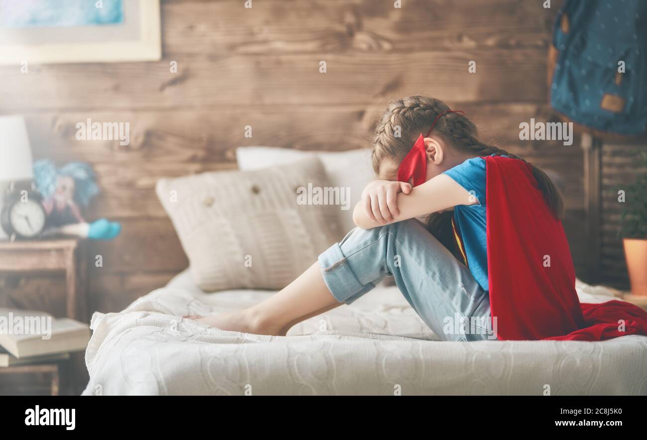 Little child crying in superhero costume in the kids room. Girl power ...
