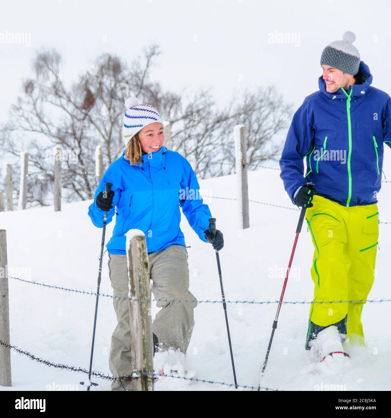 Young couple walking in snowy nature with snowshoes at a cold and ...