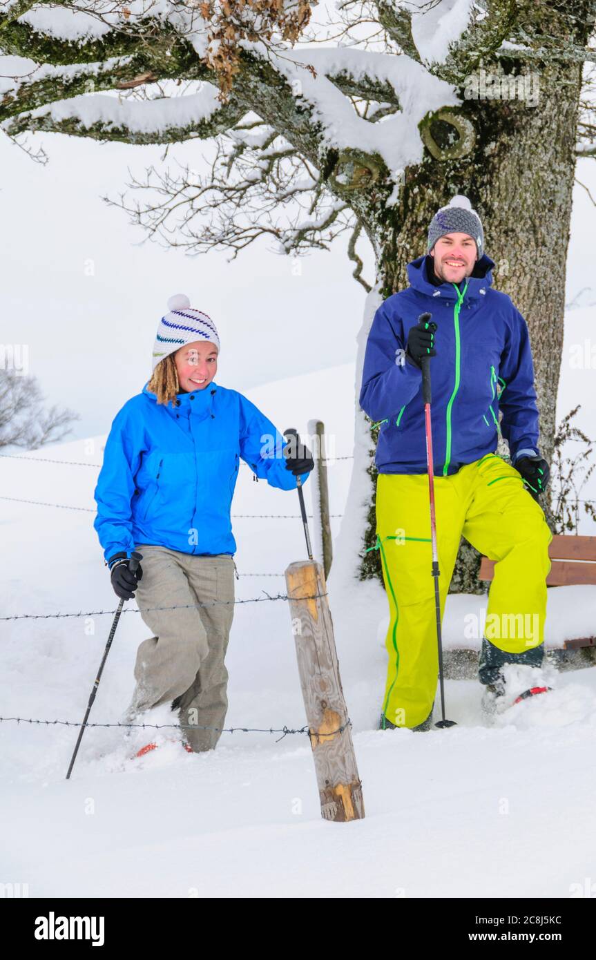 Young couple walking in snowy nature with snowshoes at a cold and ...