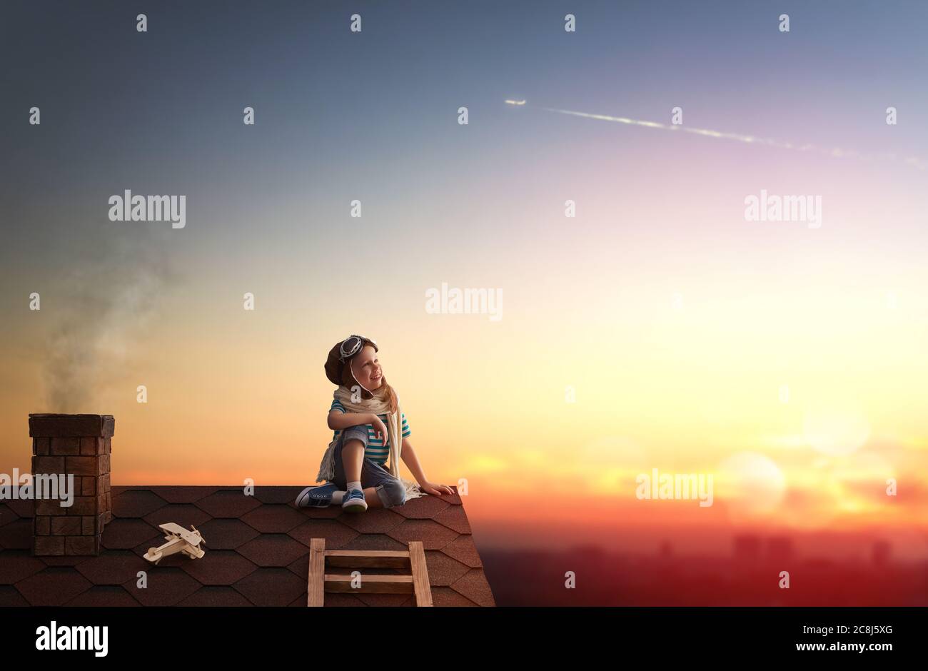 Cute little child playing on the roof of the house and looking at the ...