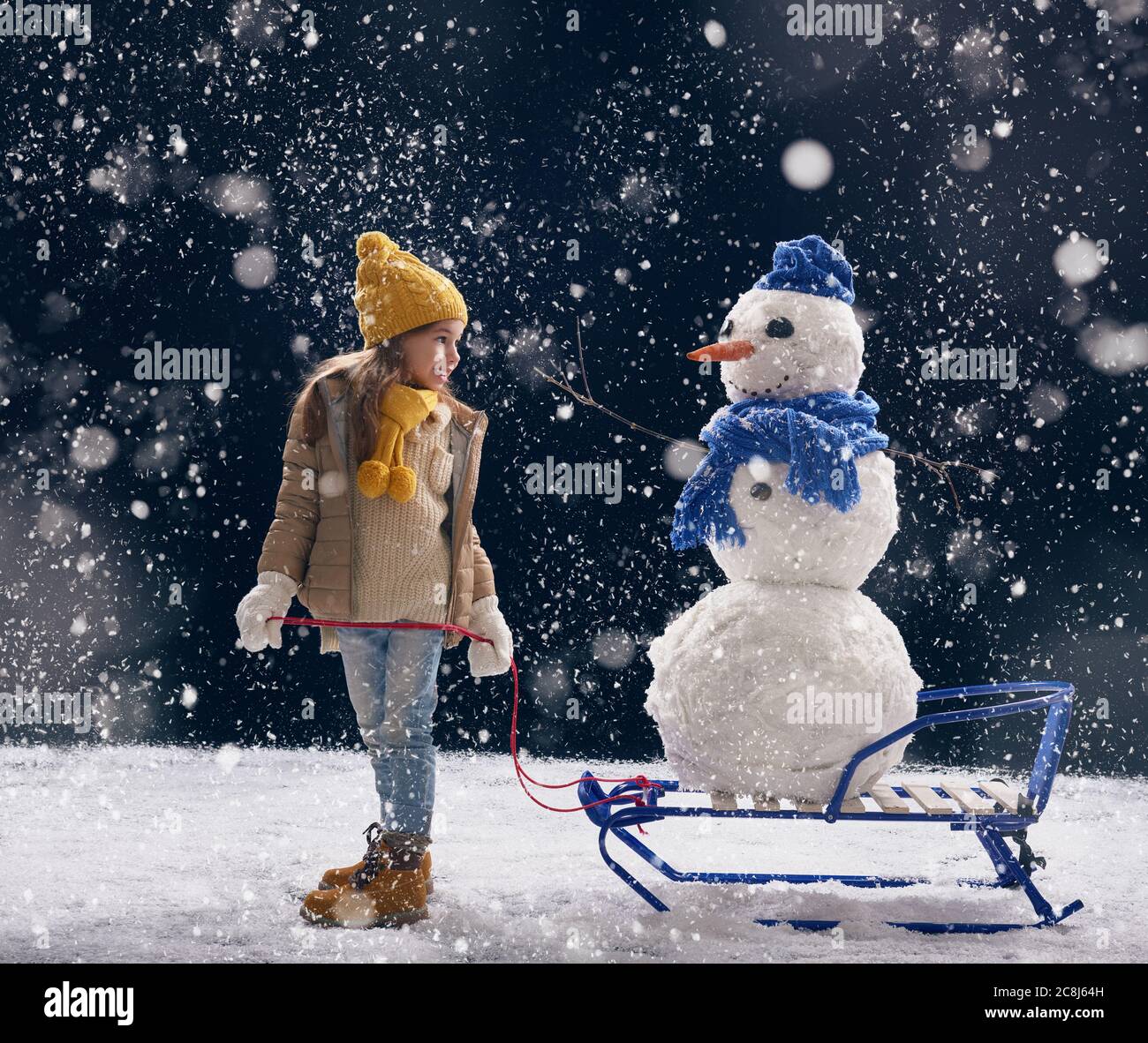 happy child girl plaing with a snowman on a snowy winter walk. child ...