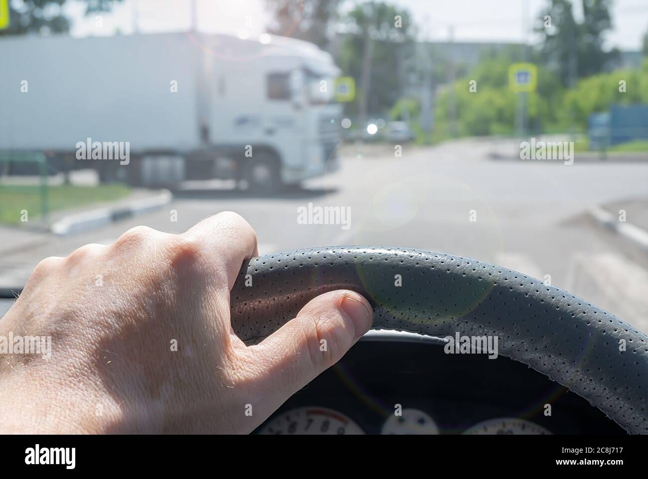 view of the driver hand at the wheel of a car at a road intersection ...