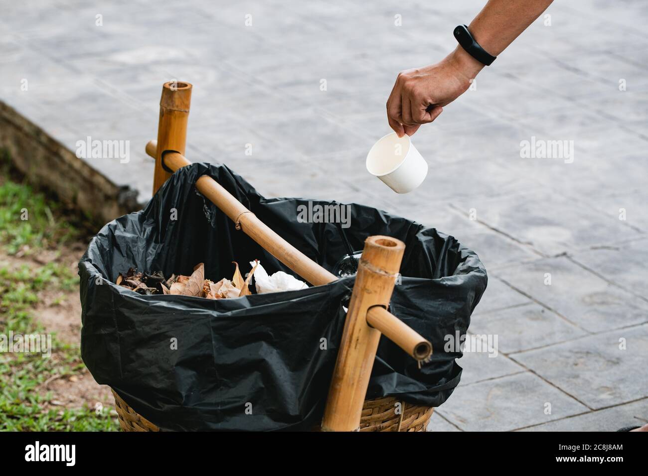 The man throwing paper cup in litter bin outdoors. Recycling concept on ...