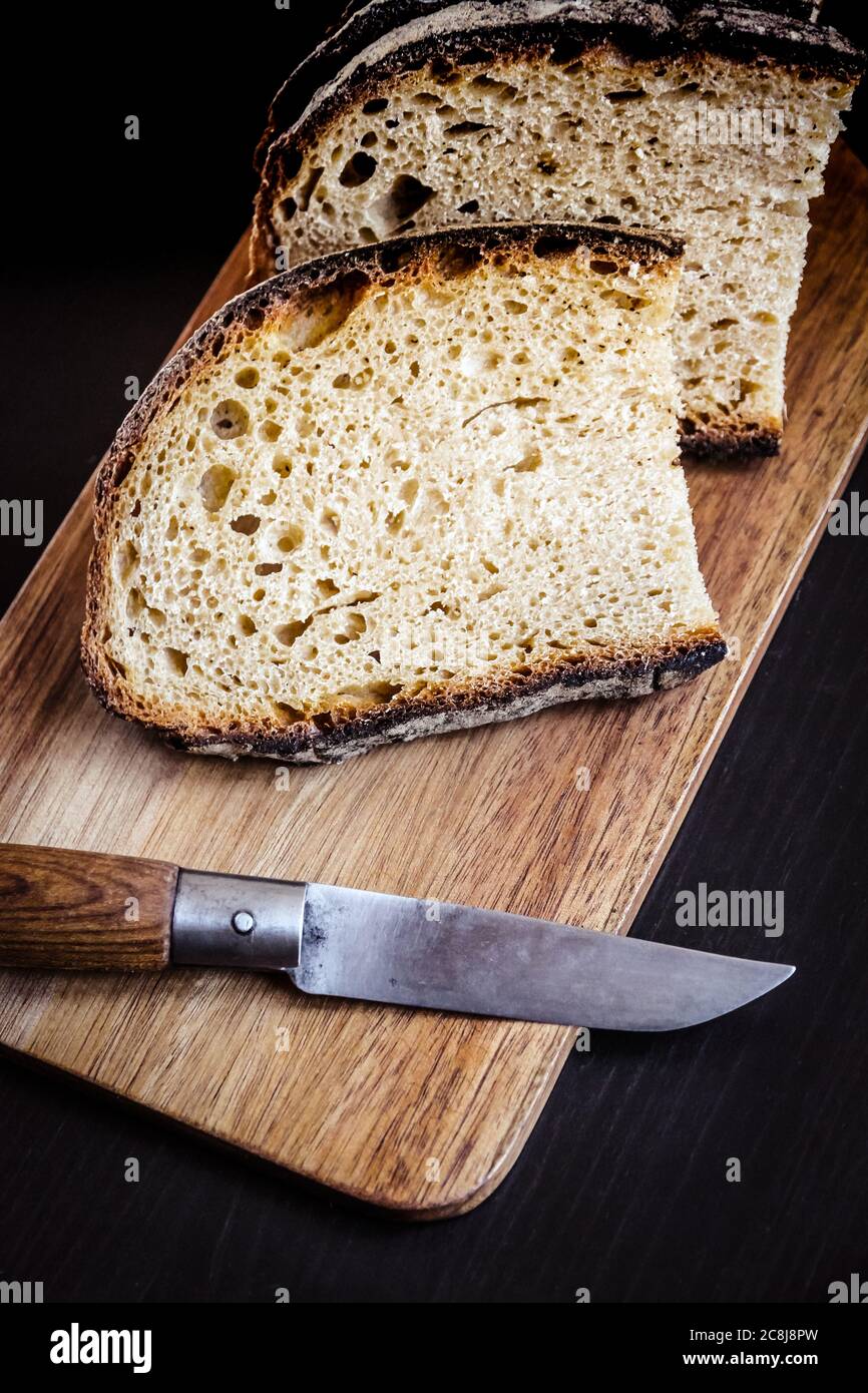 Traditional French country bread slices and pocket knife on a wooden ...