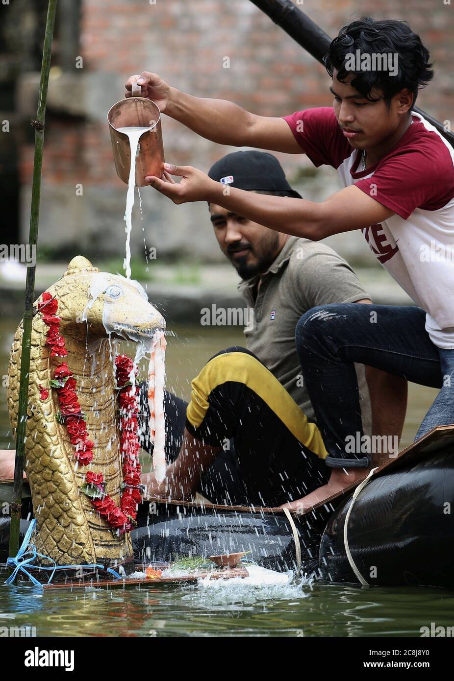 Bhaktapur, Nepal. 25th July, 2020. A devotee offers prayers as he pours ...