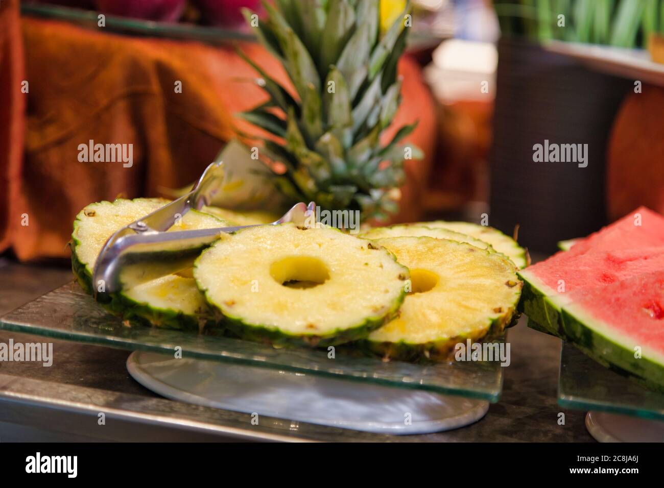 Sliced pineapple with metal tongs on top at a free buffet table in a ...