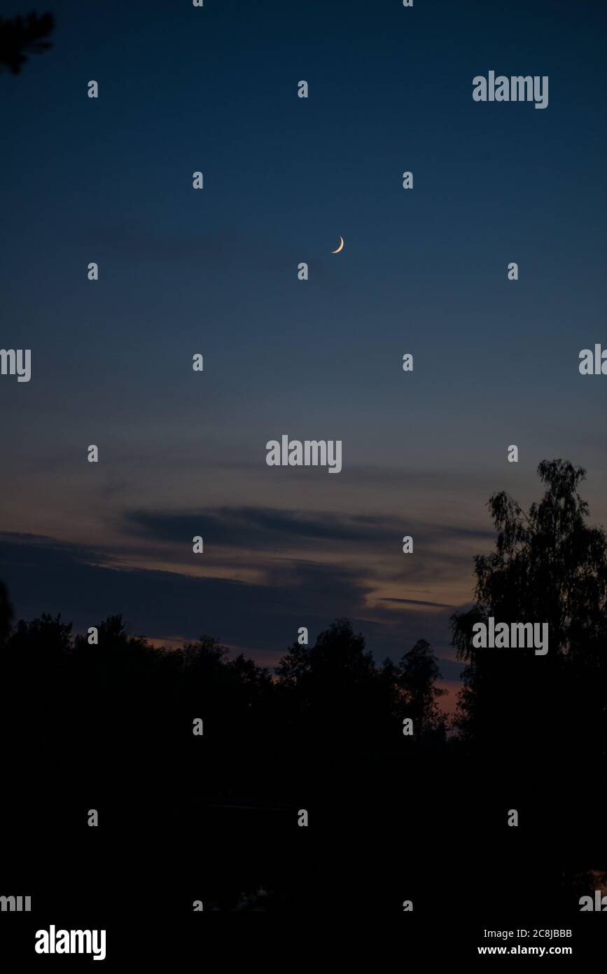 Crescent moon setting early in the evening Stock Photo - Alamy
