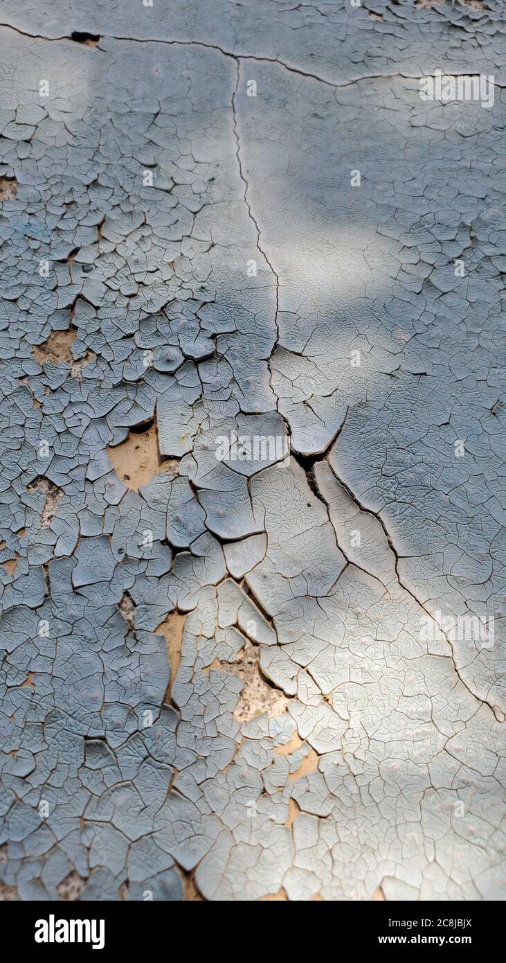 Damaged wall surface with grey blue paint cracks closeup. Grunge ...