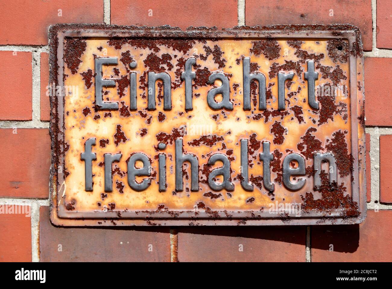 Old, rusty sign Keep driveway clear at a reddish brick wall Stock Photo ...